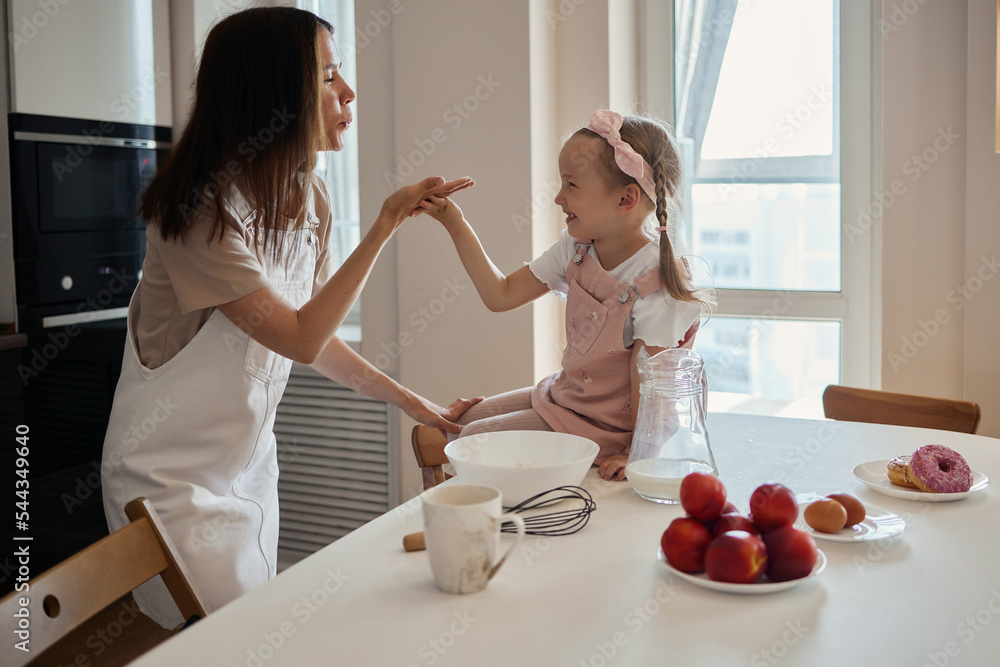 An image of a young woman and her little cute daughter are cooking in ...