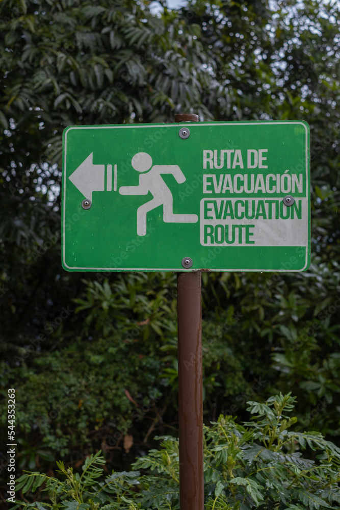 Sign in Spanish and English evacuation route with a direction arrow ...
