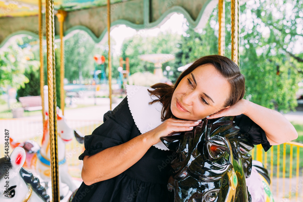 Beautiful Brunette Girl In A Black Dress Poses On A Bright Carousel ...