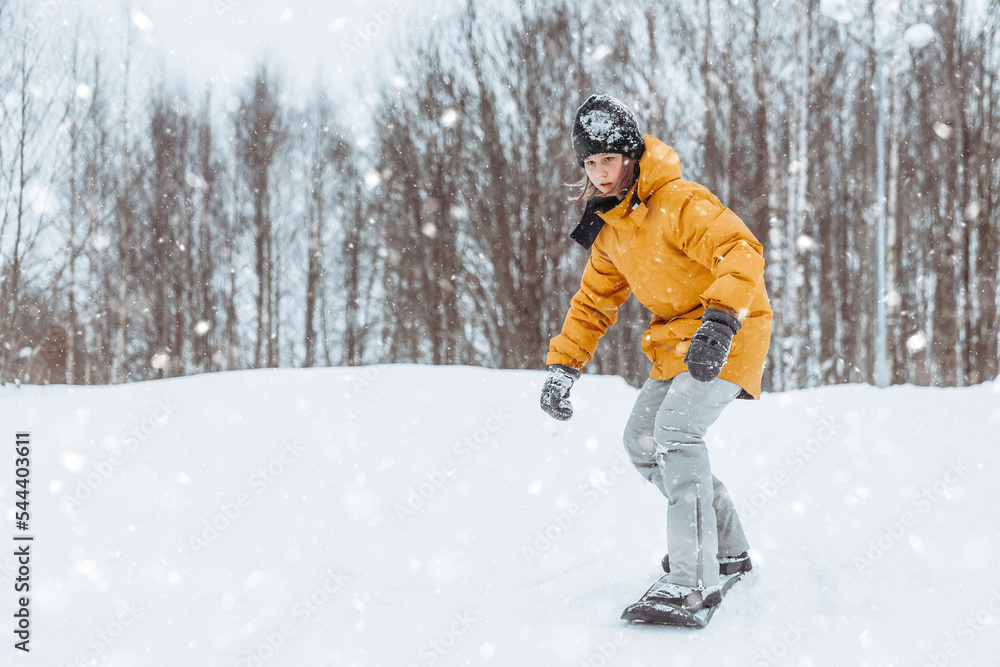 Cute teenage girl rides a snowskate in a winter park, healthy lifestyle ...