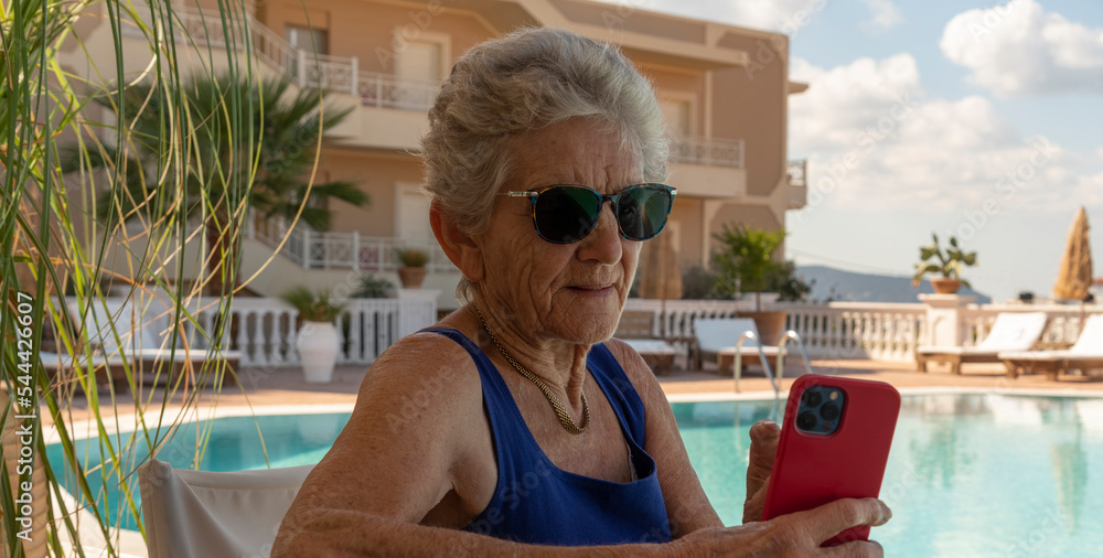 Crete Greece.2022. Elderly woman using a mobile phone by the hotel pool ...