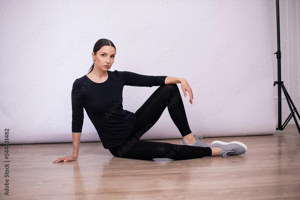 full length woman sit and show poses on the floor in black tight ...