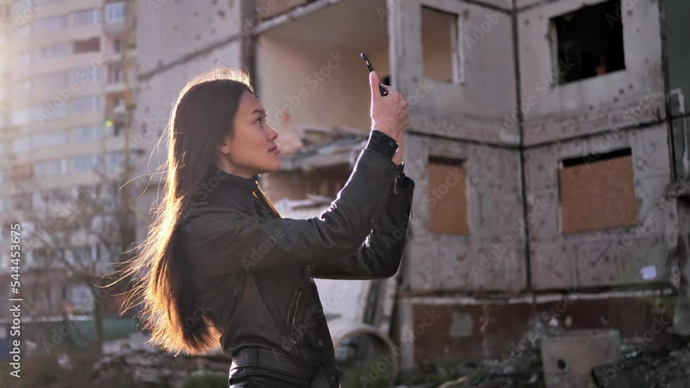 girl blogger takes photo of destroyed building on her phone. beautiful ...