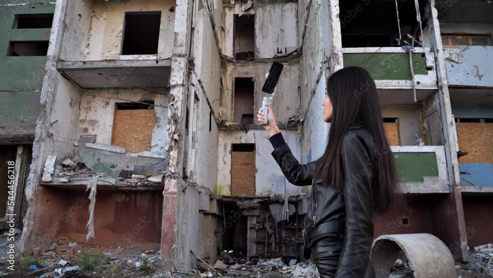 girl blogger takes photo of destroyed building on her phone. beautiful ...