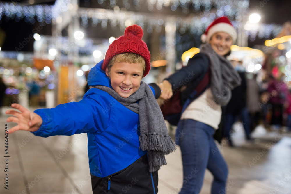 Preteen boy pulling his mom hand, demanding to buy something for him at ...