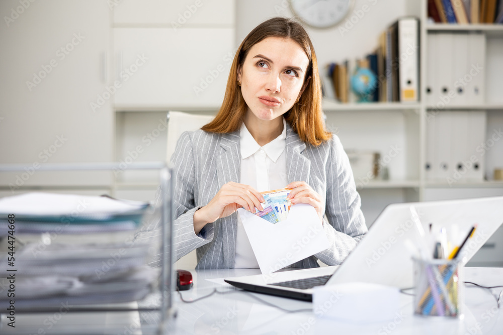 Surprised female manager takes out banknotes from an envelope in a ...