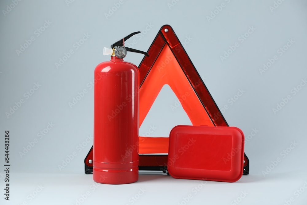 Emergency warning triangle, red fire extinguisher and first aid kit on ...
