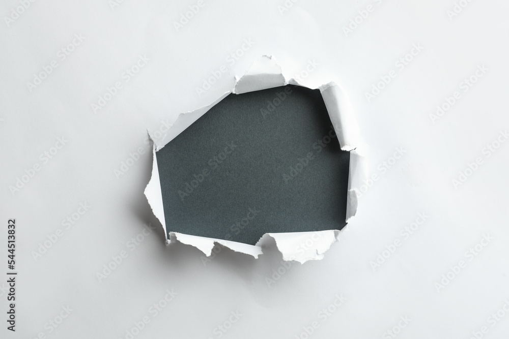 Hole in white paper on black background Stock Photo | Adobe Stock