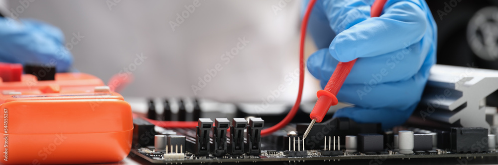 Technician measuring voltage of in computer mainboard using electronic ...