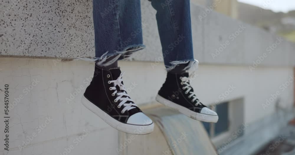 Building, shoes and man on a rooftop in the city sitting outside for a ...