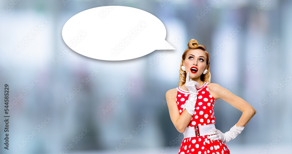 Studio portrait image of thinking woman in red pin up dress. Blond ...