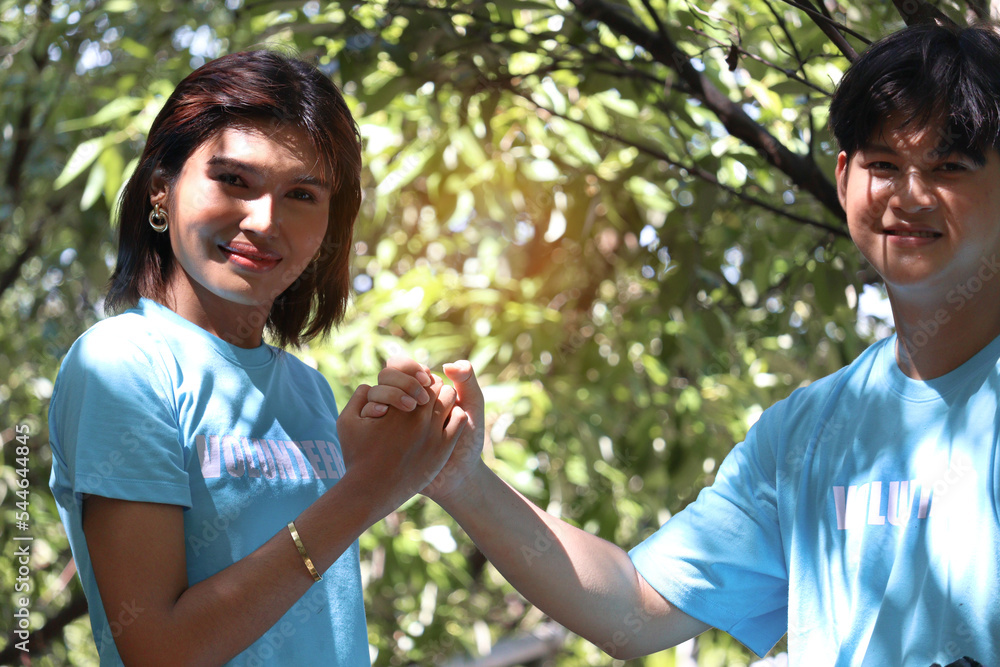 Two volunteers in blue t-shirt holding hands together after doing ...