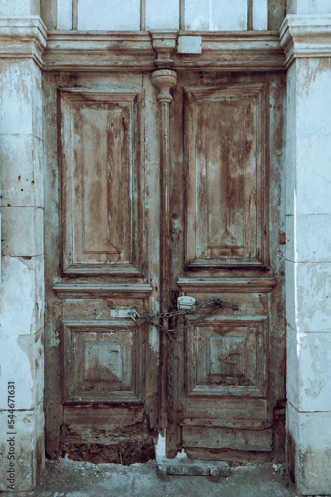 Very old obsolete wooden front door with locks and metal chain in stone ...