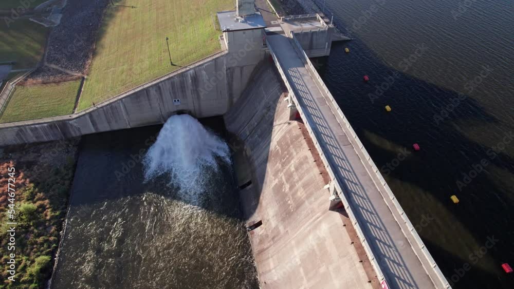 Concrete walkway and path above high powered dam next to reservoir and ...