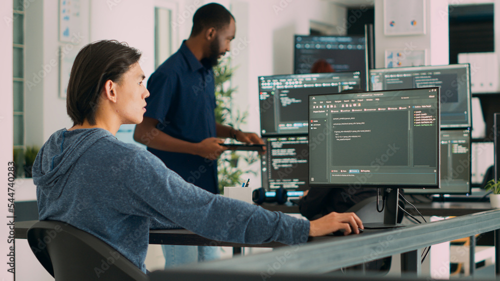 Software developer typing learning app code on computer, sitting at desk in big data office ...