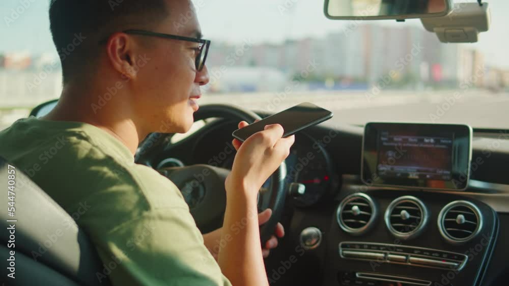 Young man driver recording voice message on phone. Car sharing concept ...