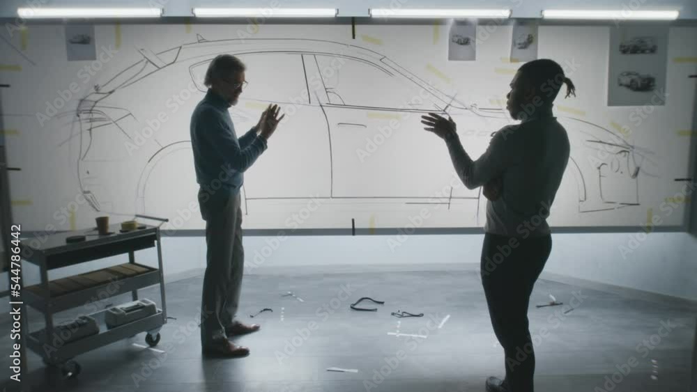 Two diverse automotive male designers discussing sketch, drawing with ...