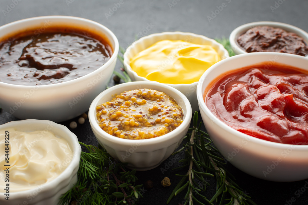 Different types of sauces in bowls with seasonings, rosemary and dill ...