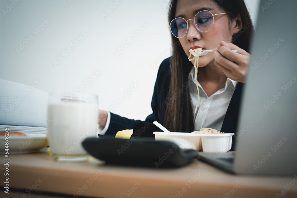 Busy and tired businesswoman eating spaghetti for lunch at the Desk ...