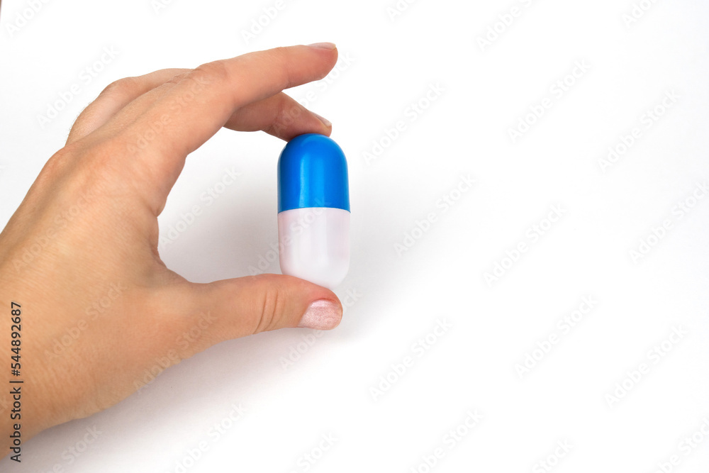 huge pill capsule in a female hand on a white background. medical drug ...