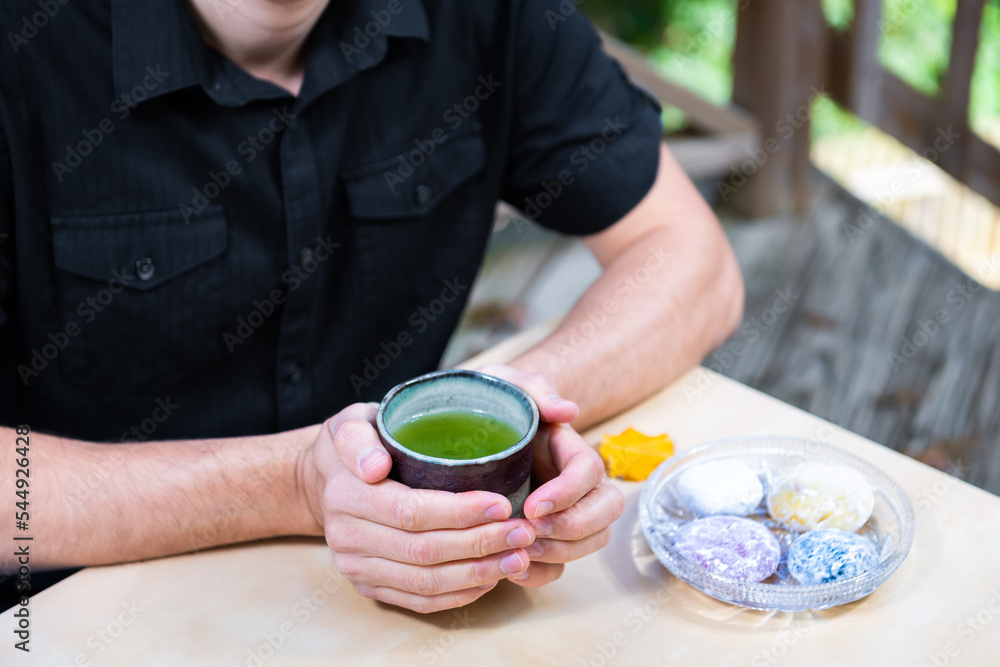 Man sitting at table with closeup of hands holding matcha green tea cup ...