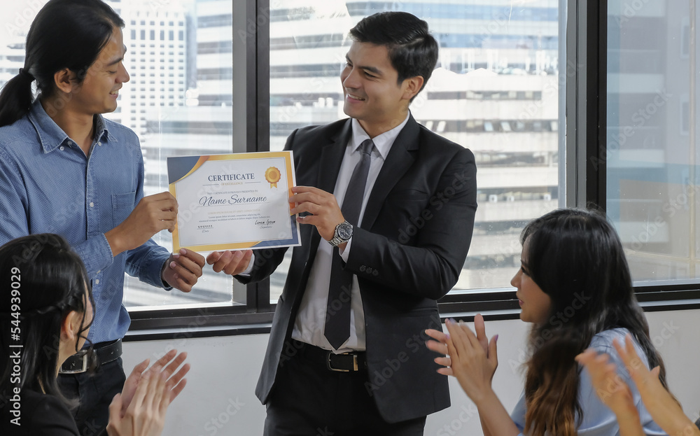 Young caucasian manager in suit giving mock up certificate to asian ...