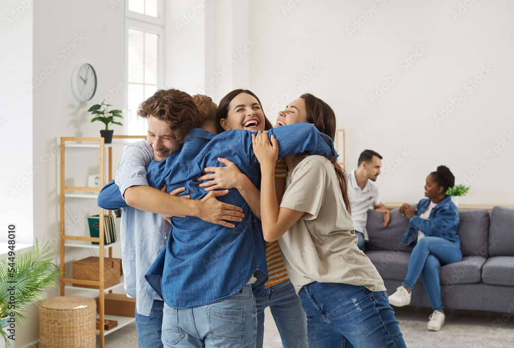 Happy friends who haven't seen each other for long time are hugging ...