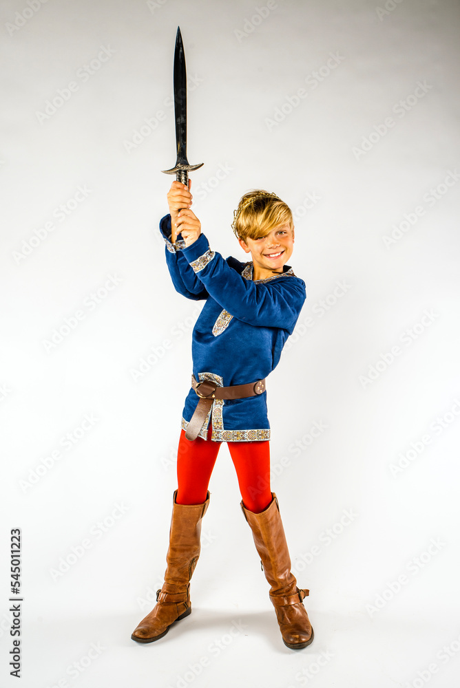 Cute young boy dressed as a cosplay prince holding his sword high and ...