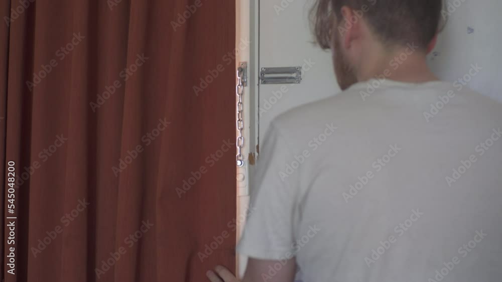 Man peers through window of motel room and locks door (medium shot 35mm ...