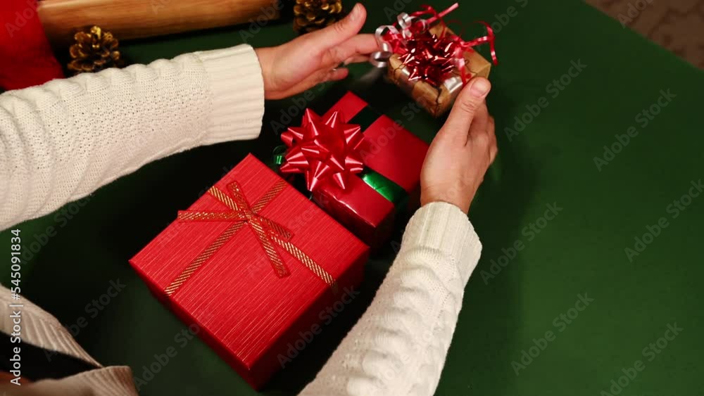 Top view woman in beige sweater, laying out gift boxes in a Christmas ...