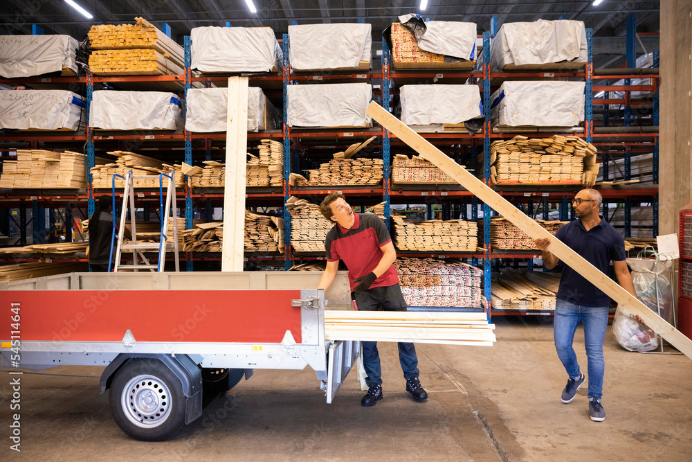 Male customer loading wooden plank in trailer at hardware store Stock ...