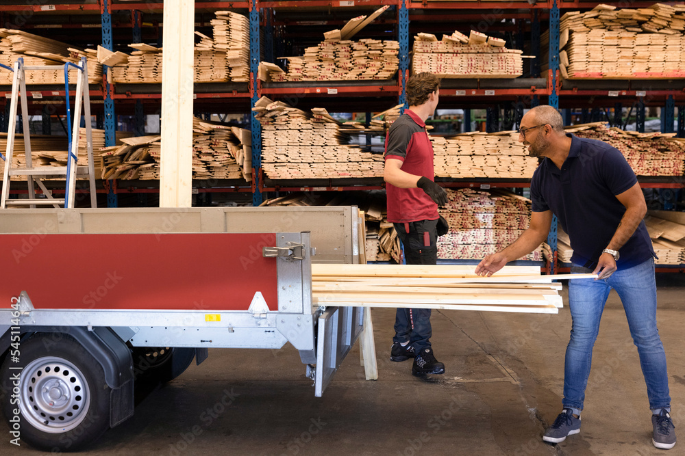 Mature man loading plank in vehicle trailer at hardware store Stock ...
