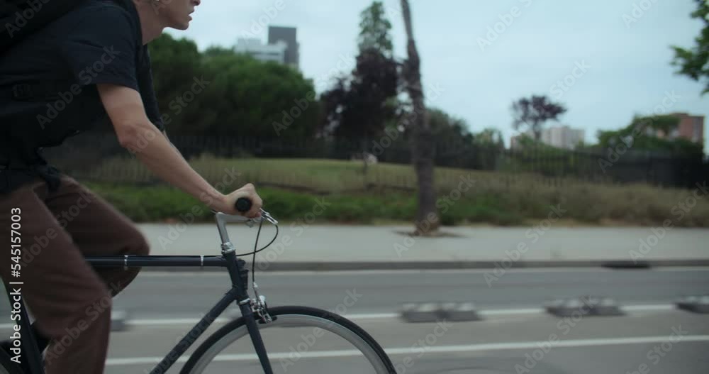 Side shot of commuter cyclist ride in city. Young man ride a simple ...