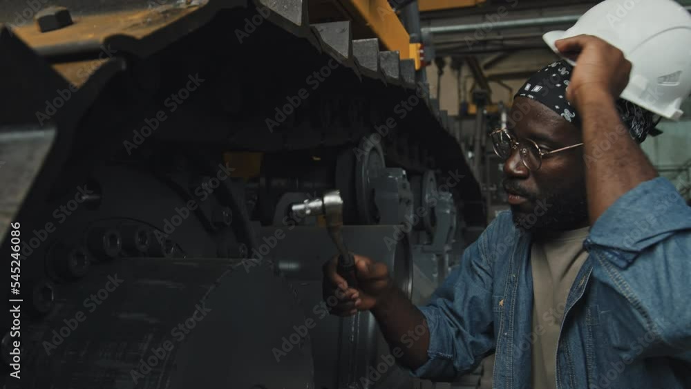 Hard working African American mechanic in denim shirt and hard hat ...