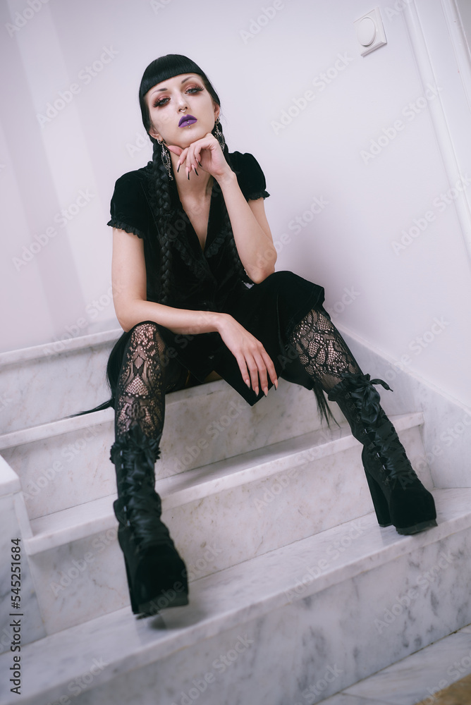 Gothic vampire girl standing on marble staircase, posing in a black ...