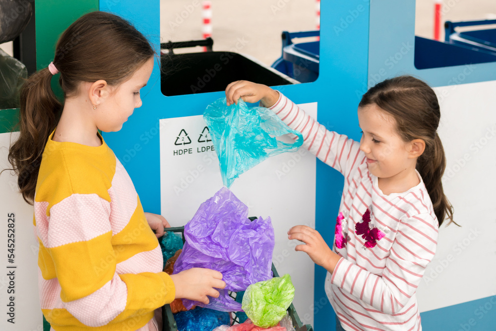 Girls taking out plastic trash in recycling centre. Children putting ...