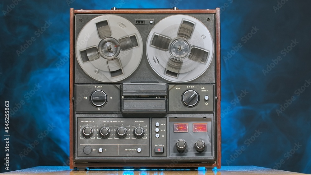 Retro reel to reel tape recorder on studio background with blue light ...