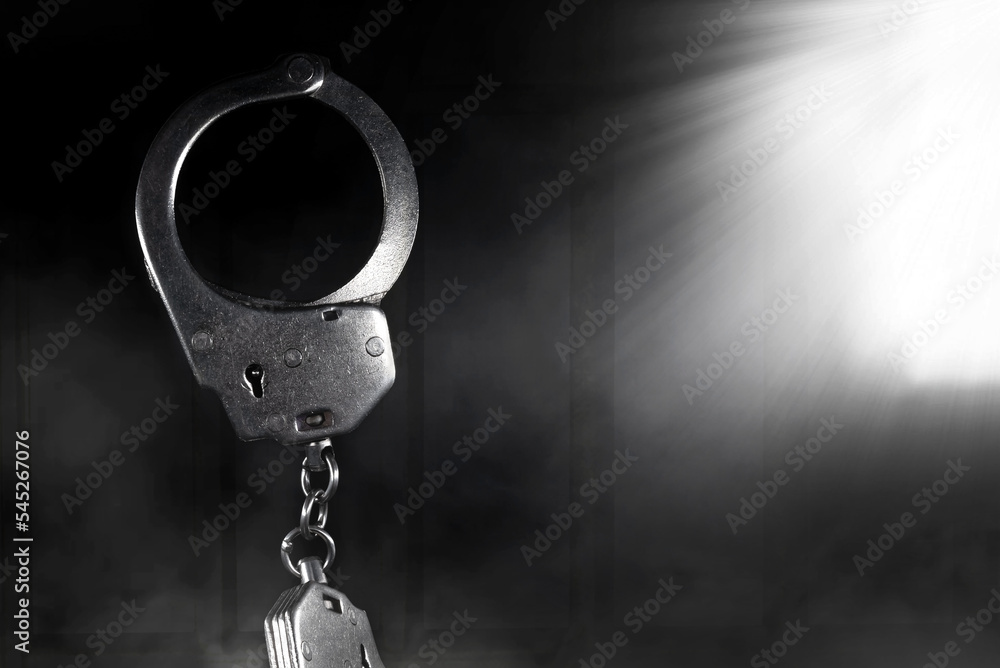 Handcuffs in a dark prison cell with light from the window. Handcuffs ...