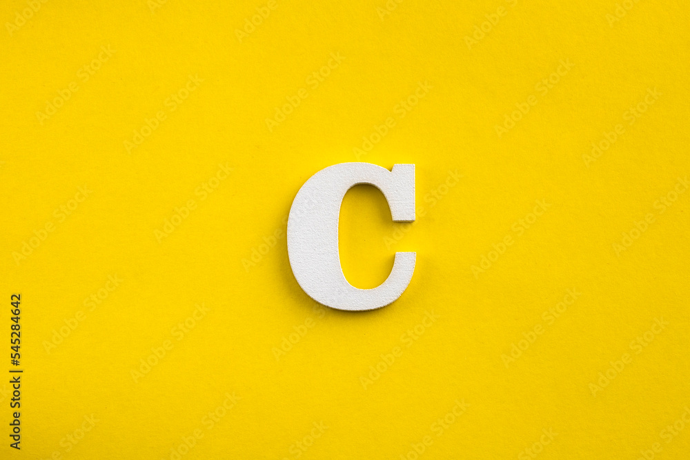 Alphabet letter C - White wood letter on yellow colored background ...