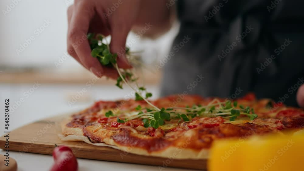 The cook sprinkles herbs on the cooked pizza, the pizza is ready, The ...