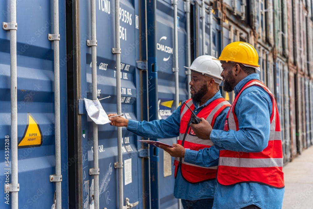 Two black african male professional engineers inspecting a container in ...