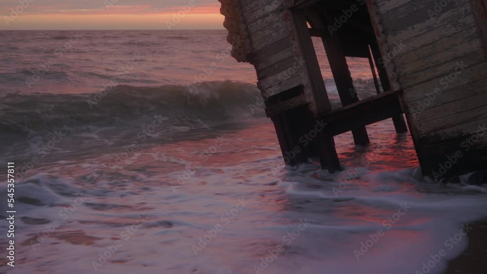Mysterious vintage flooded leaning wooden house washed by sea waves, at ...