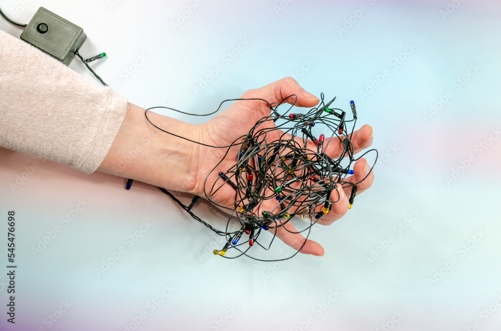 Hand holds tangled Christmas tree garland. Woman was electrocuted ...