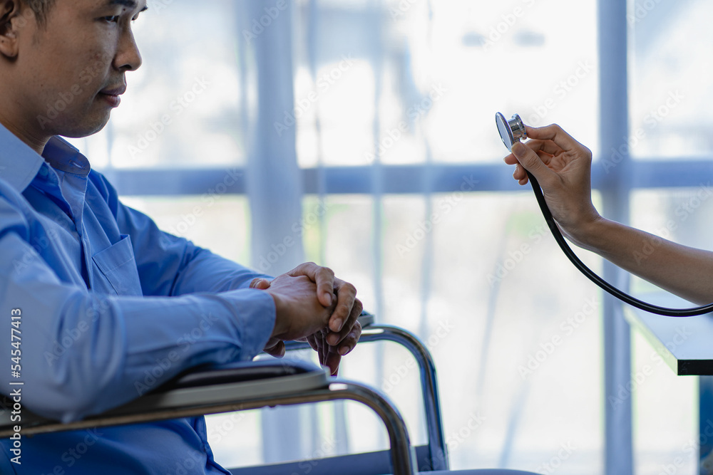 Foto de Asian female doctor using a stethoscope to examine a male ...