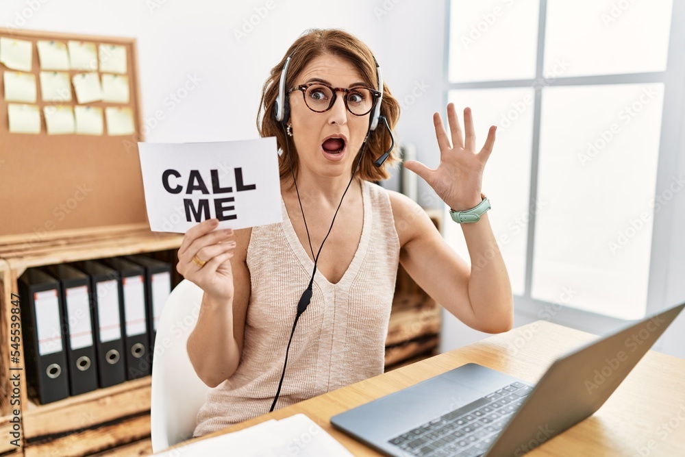 Middle age brunette woman wearing operator headset holding call me ...