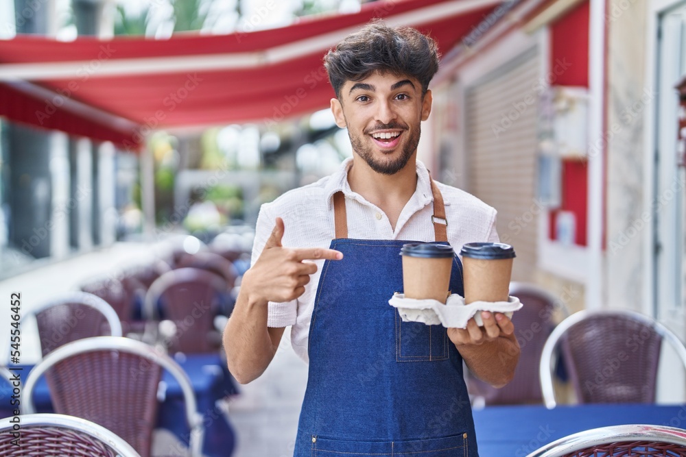Arab man with beard wearing waiter apron at restaurant terrace smiling ...