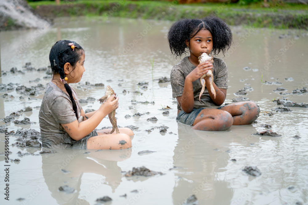 African American girl sit and kiss frog during fun play in mud ...