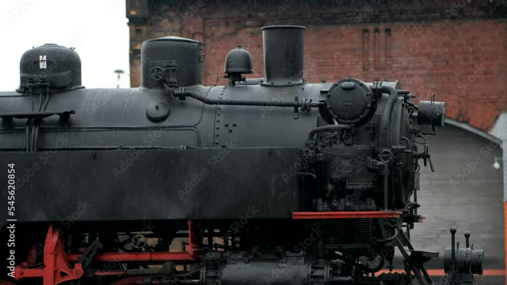 Black steam locomotive with steam propulsion system, in the rain at the ...