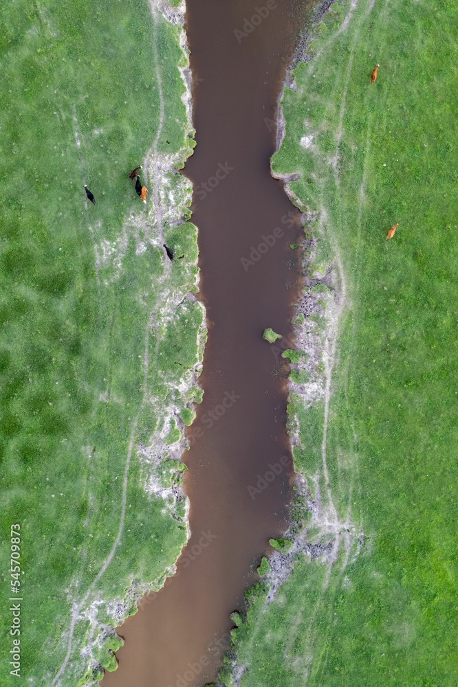 Aerial view of a river stream passing through an open field in Entre ...