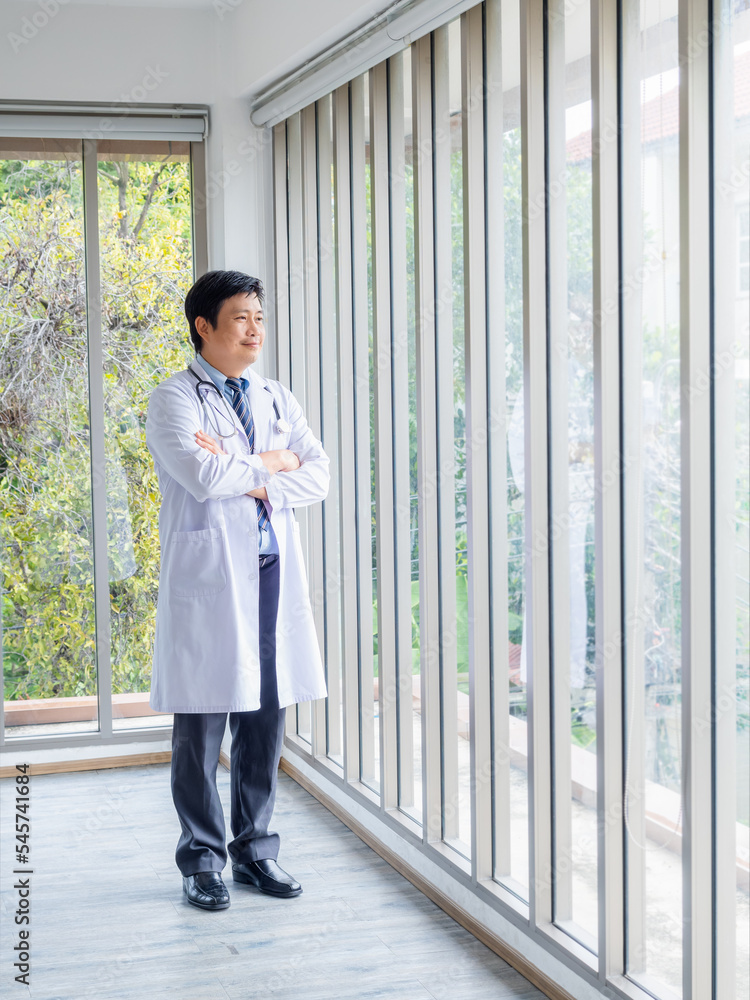 Smiling Asian man doctor portrait in white coat standing alone with ...